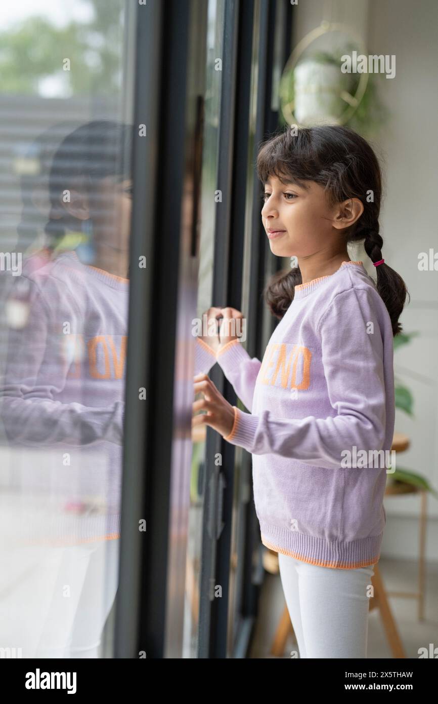 Little girl looking out window Stock Photo - Alamy