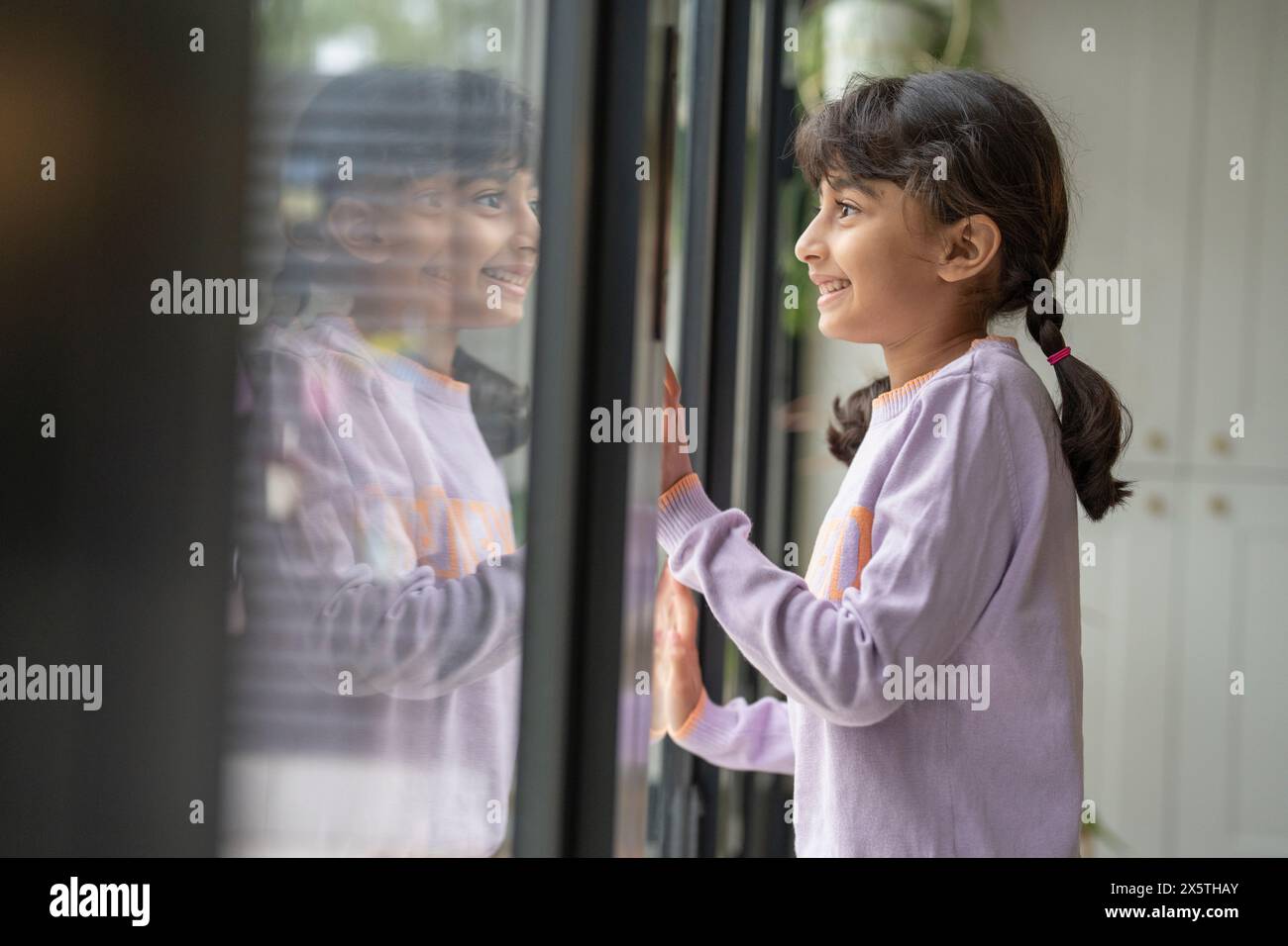Little girl looking out window Stock Photo - Alamy