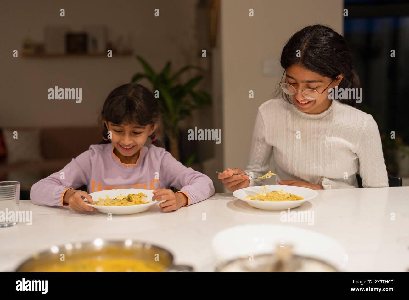Sisters eating meal at table Stock Photo - Alamy
