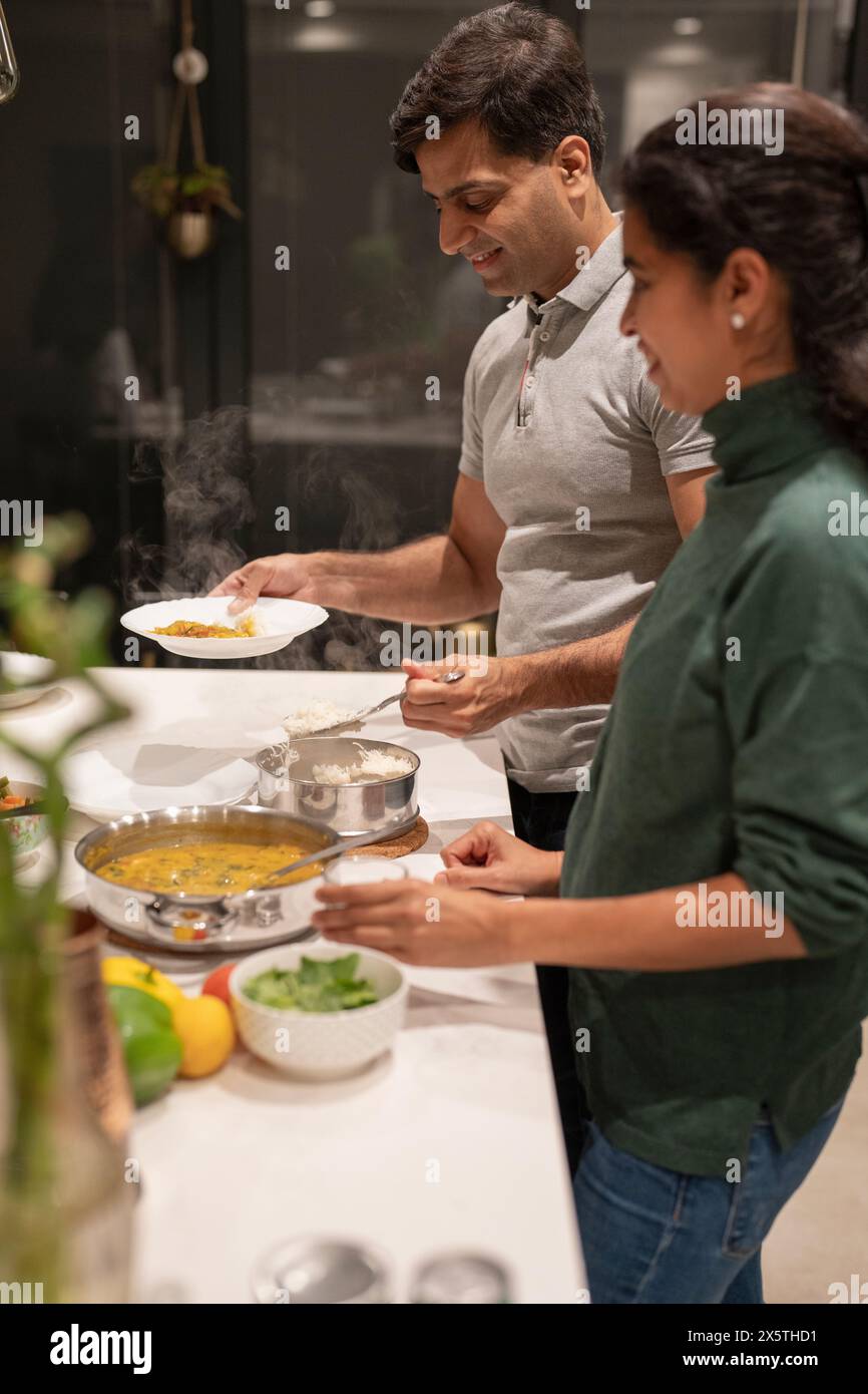 Husband and wife putting food on plates Stock Photo - Alamy