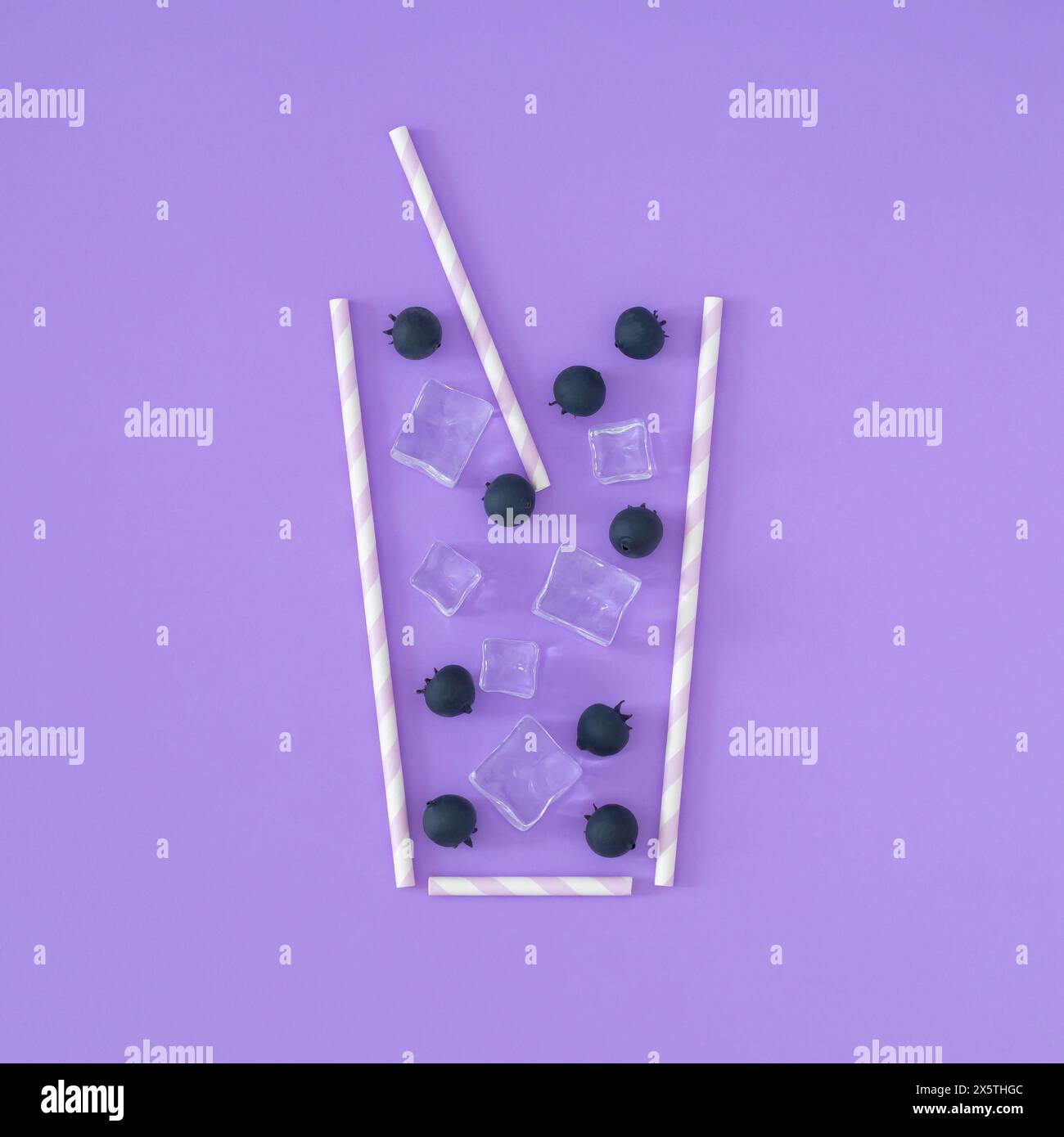 Creative summer composition made with blueberries, ice cubes and drinking straw on purple ...