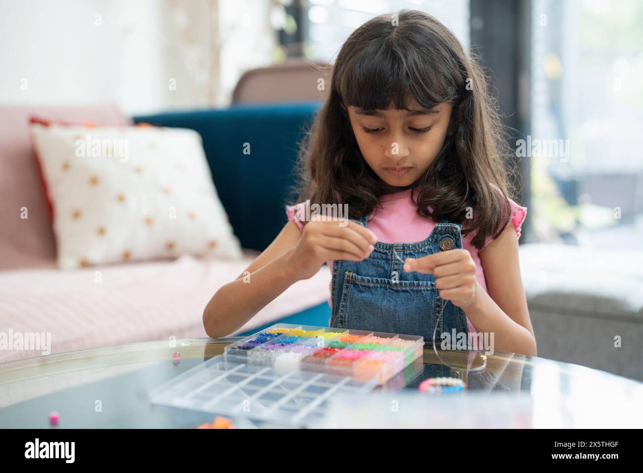 Little girl playing with beads in living room Stock Photo - Alamy
