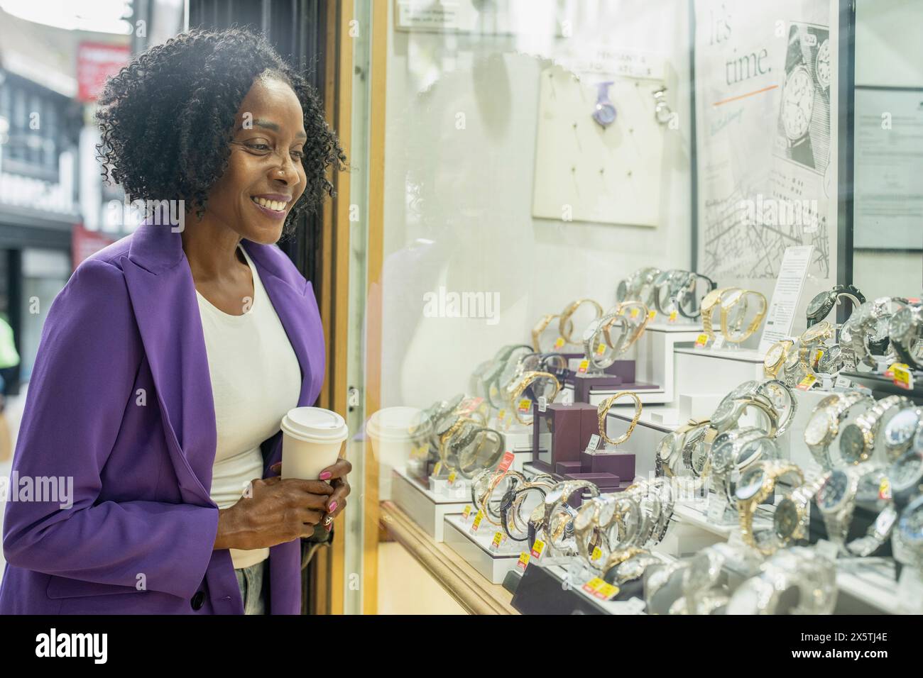 Woman looking through store window on wristwatch display Stock Photo ...