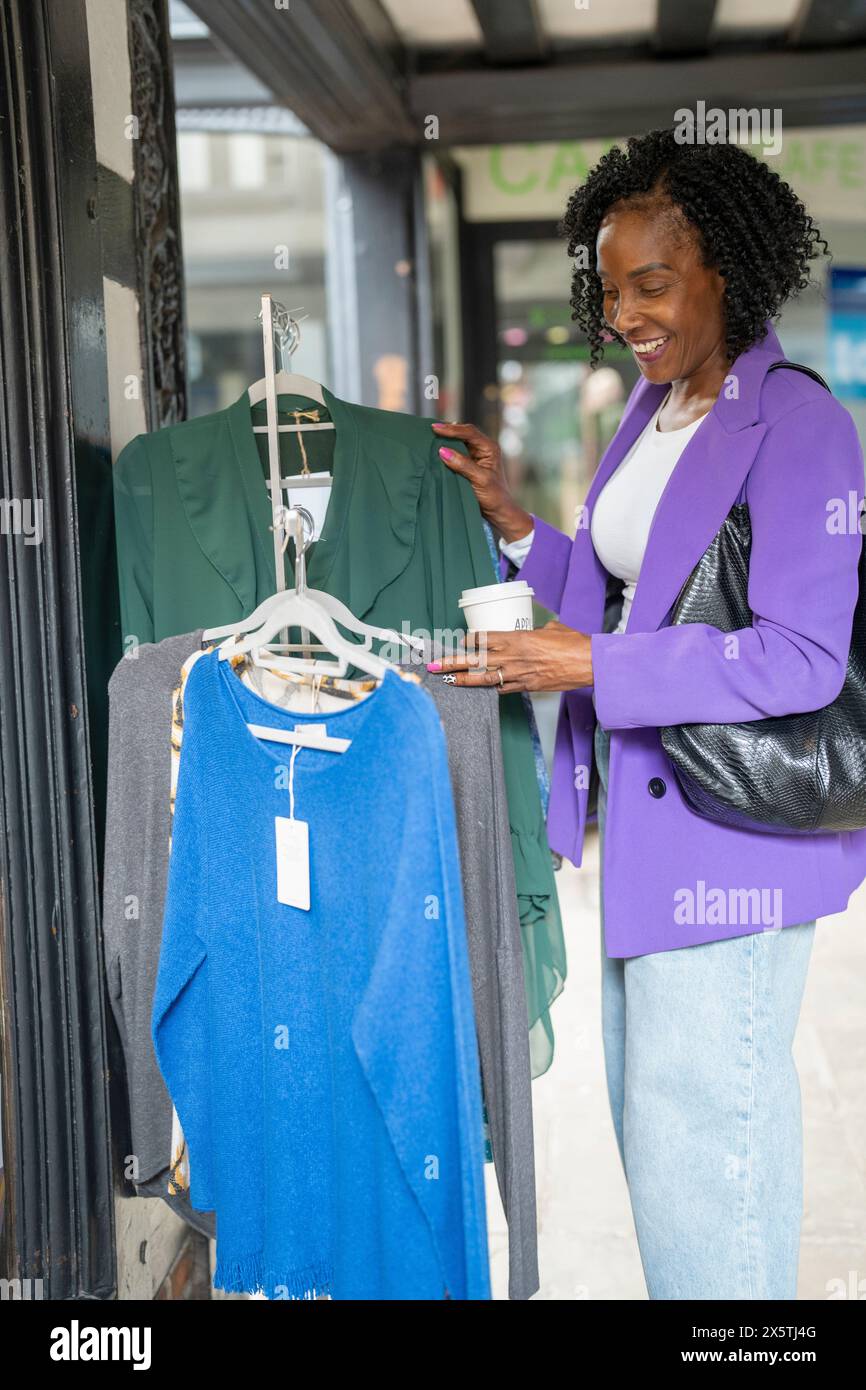 Smiling woman looking at clothes in store Stock Photo - Alamy