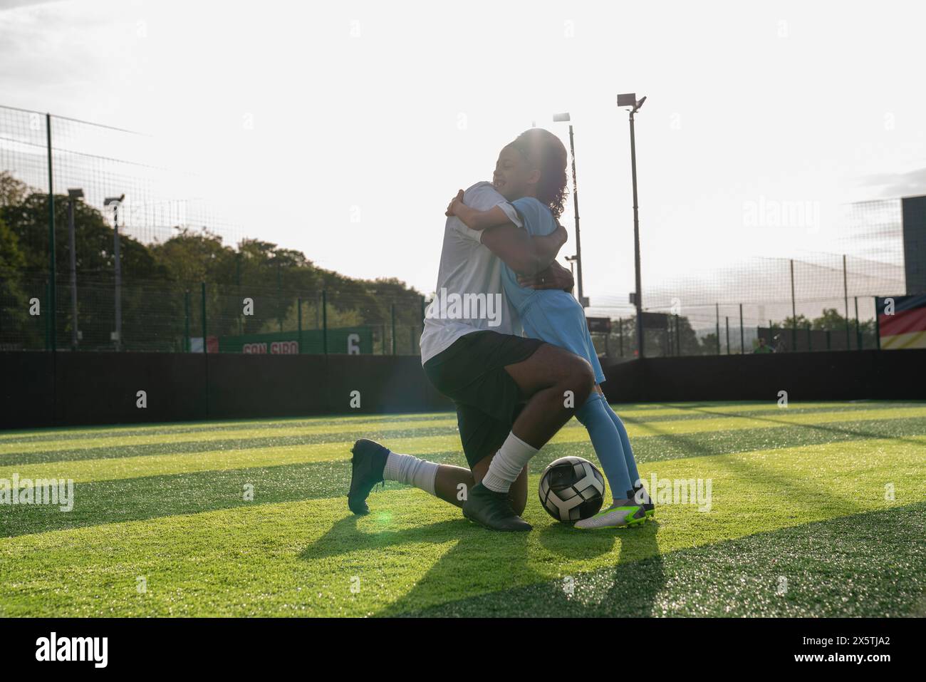 Coach and girl (6-7) hugging on soccer field Stock Photo - Alamy