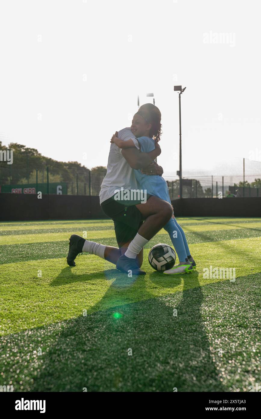 Coach and girl (6-7) hugging on soccer field Stock Photo - Alamy