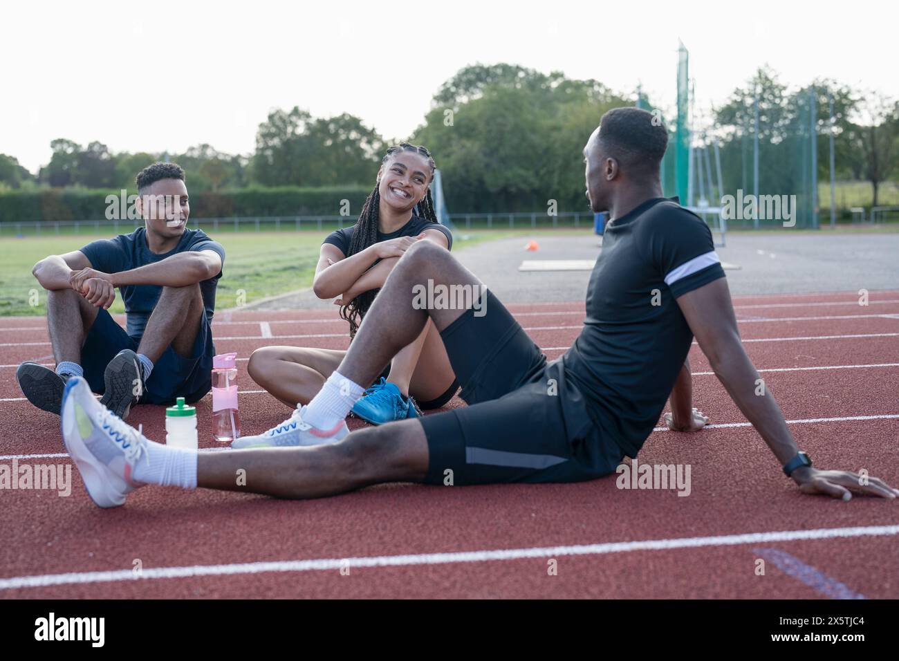 Group of athletes resting at sports track after training Stock Photo ...