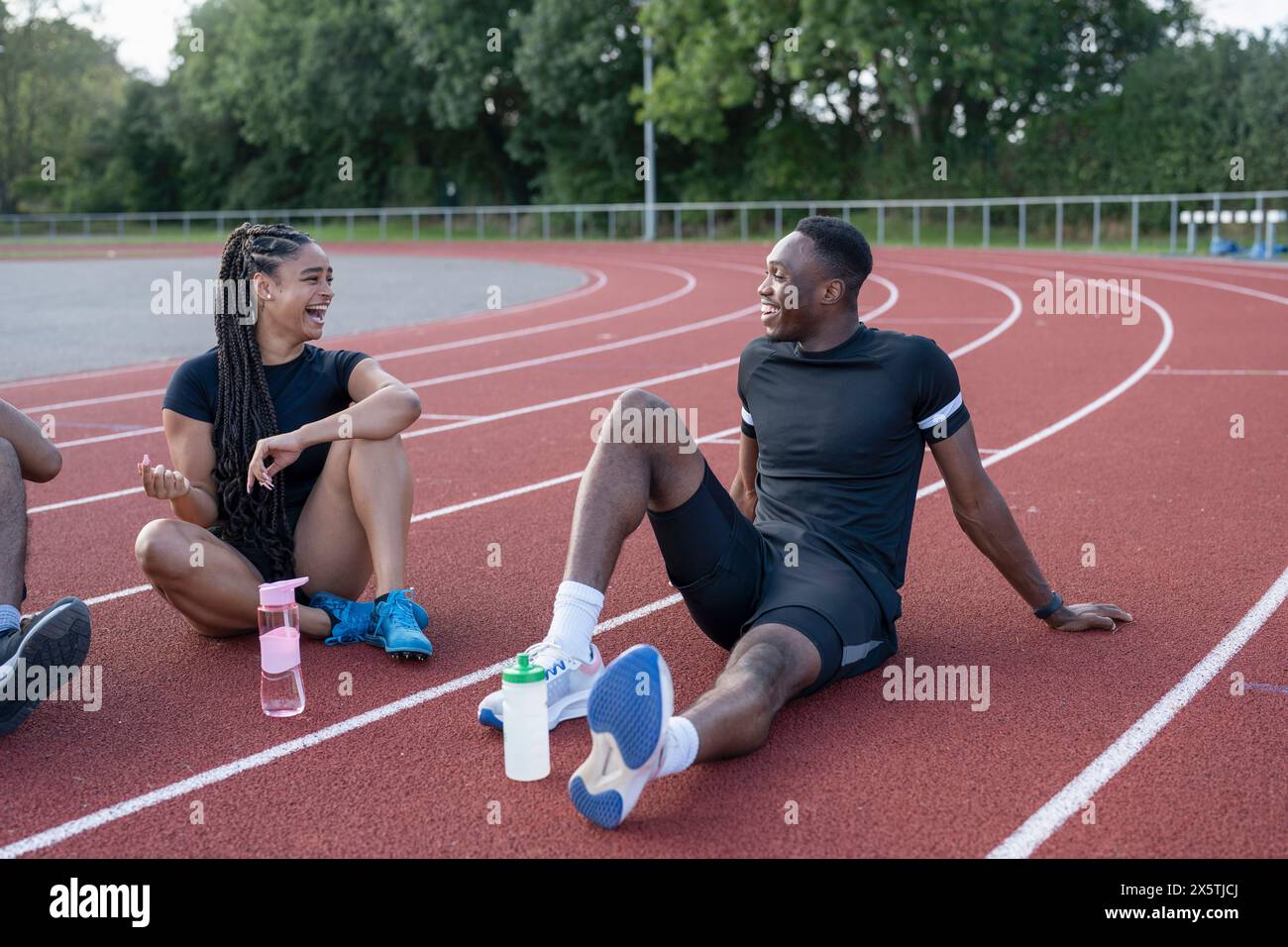 Group of athletes resting at sports track after training Stock Photo ...