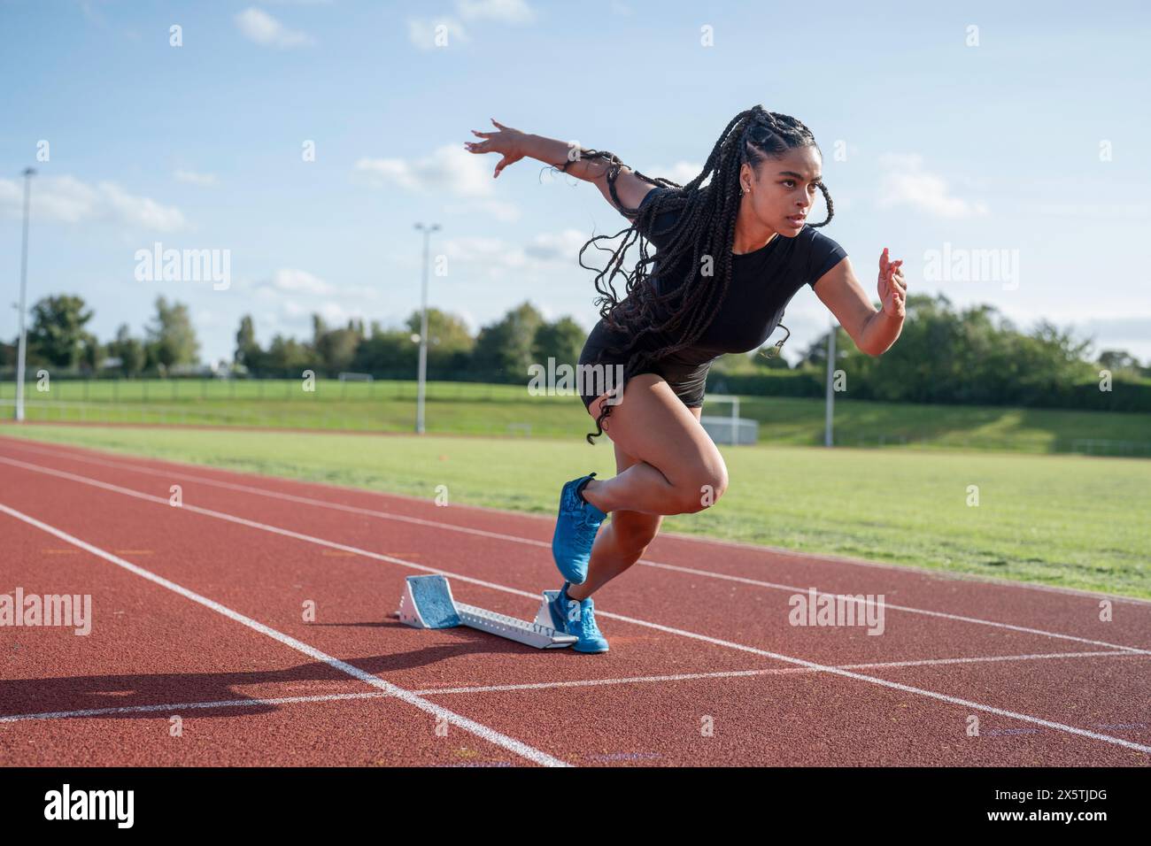 Female athlete sprinting off starting line at stadium Stock Photo - Alamy