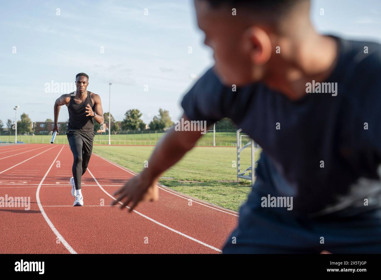 Two athletes running in relay race Stock Photo - Alamy
