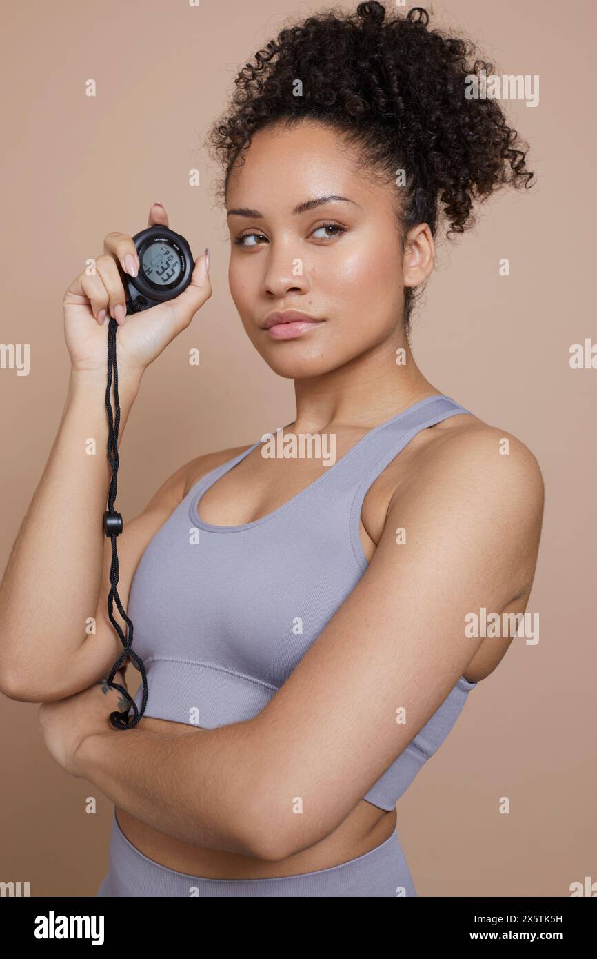 Studio portrait of athletic woman holding digital stopwatch Stock Photo ...