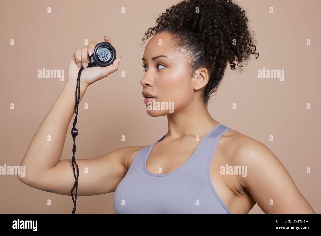 Studio portrait of athletic woman holding digital stopwatch Stock Photo ...