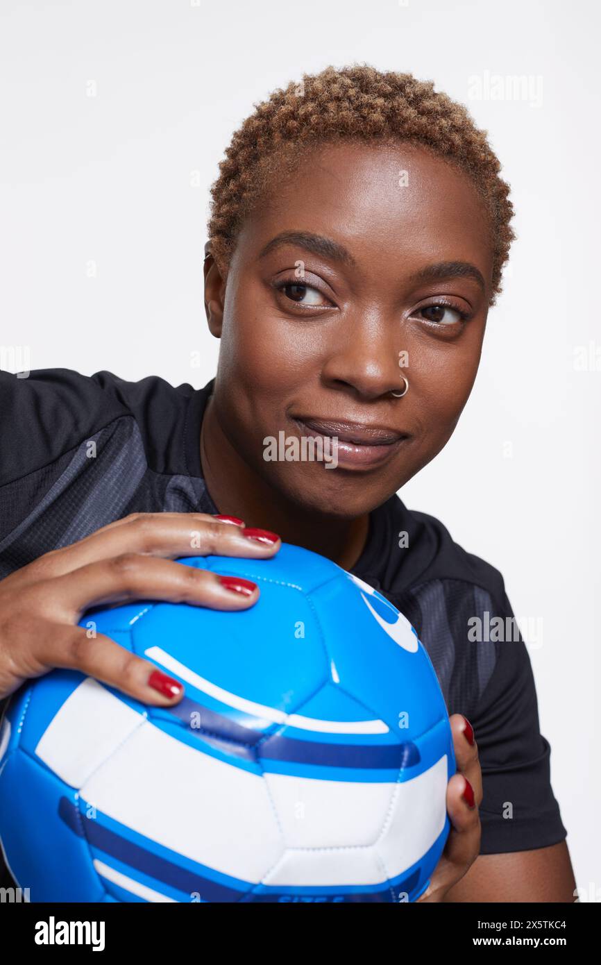 Studio portrait of smiling female soccer player with ball Stock Photo ...