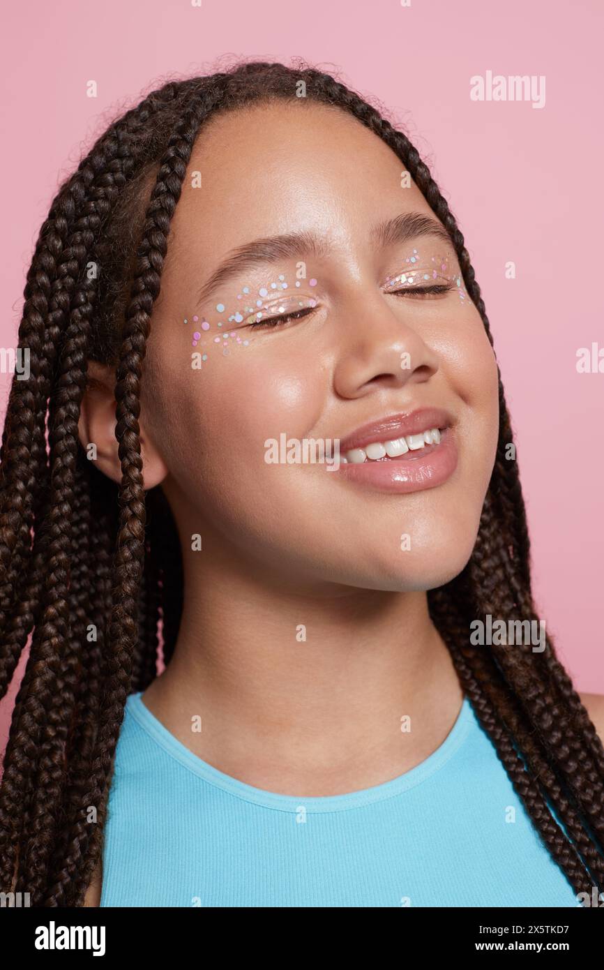 Studio portrait of girl with braids and decorative stickers on face ...