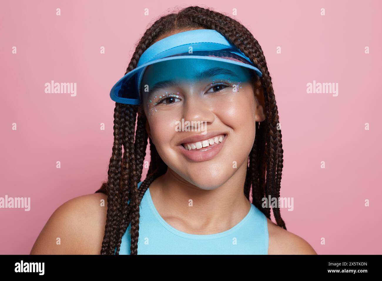 Studio portrait of smiling girl wearing sun visor Stock Photo - Alamy