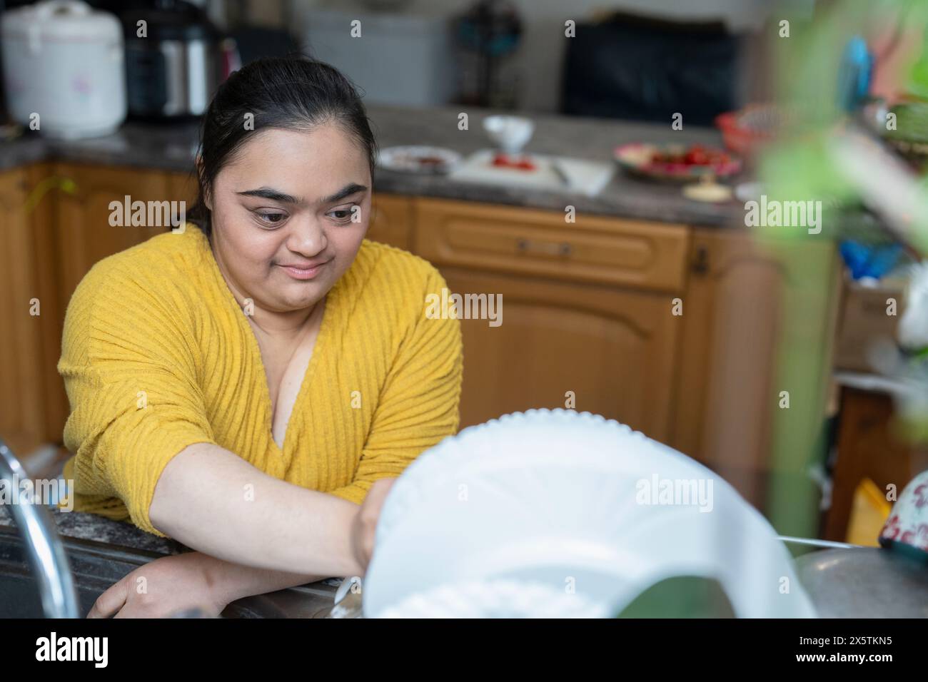 Young woman with down syndrome washing dishes at home Stock Photo - Alamy