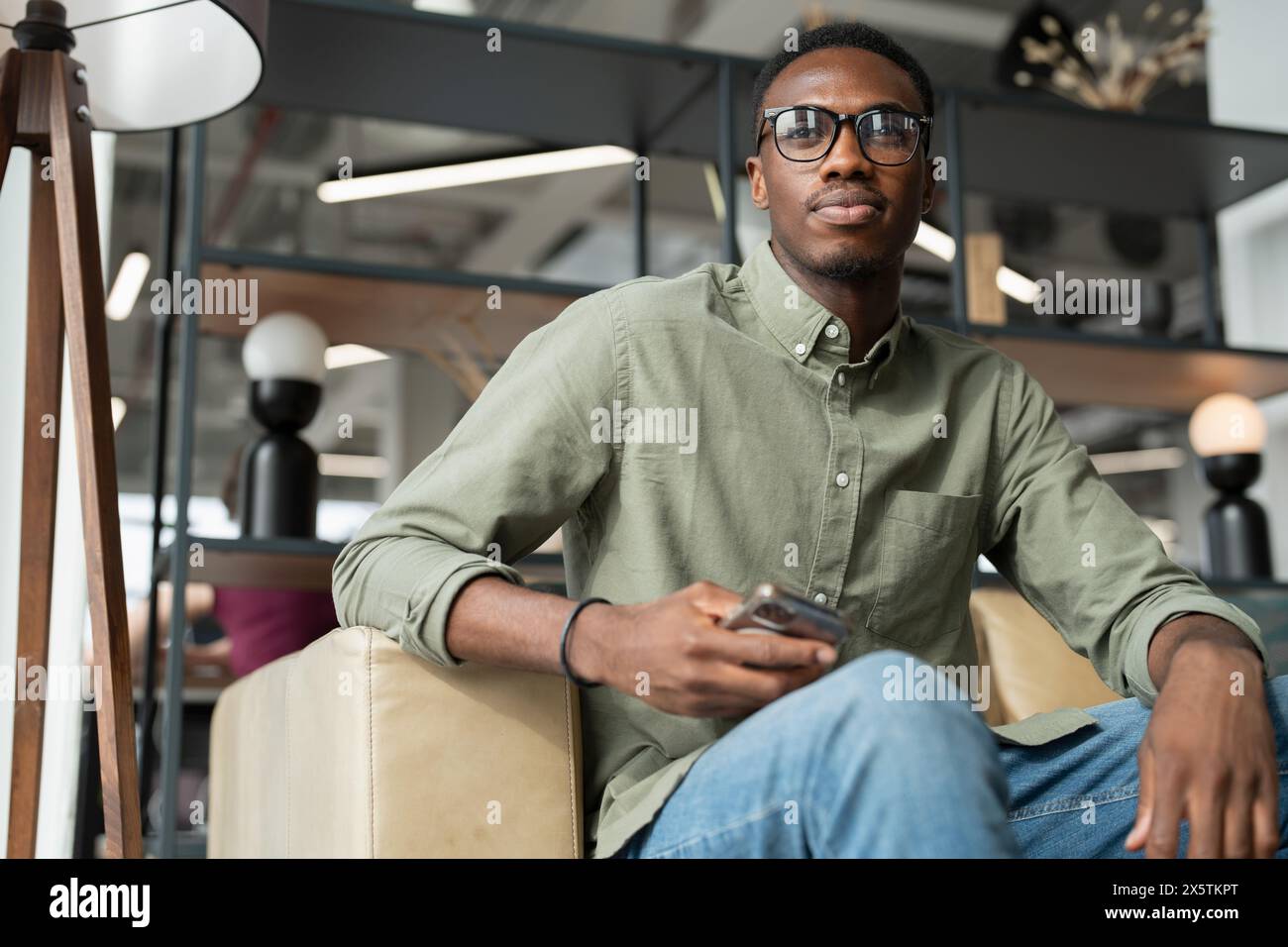 Young man sitting in office lounge Stock Photo - Alamy
