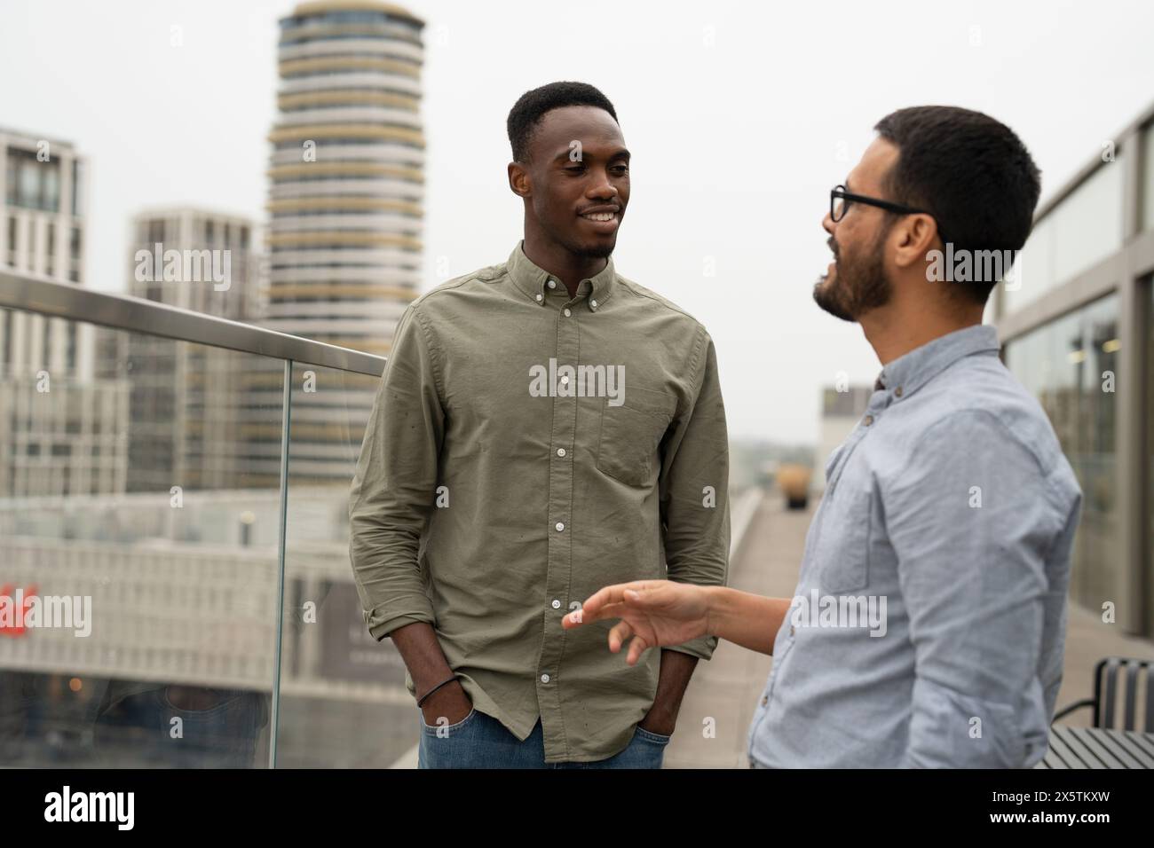 Two office workers talking against office buildings Stock Photo - Alamy