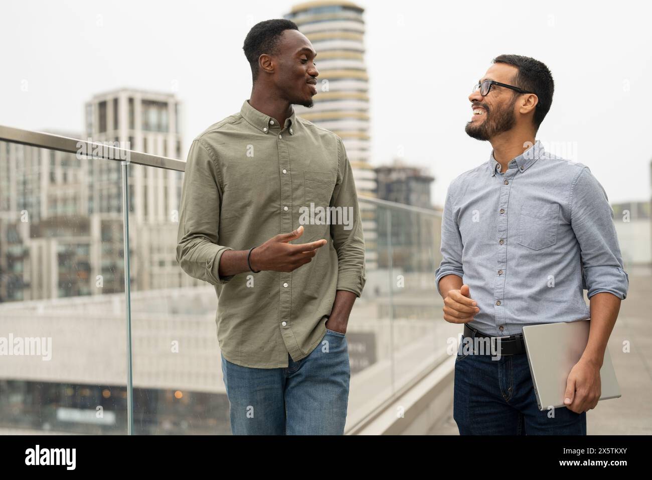 Two office workers talking against office buildings Stock Photo - Alamy