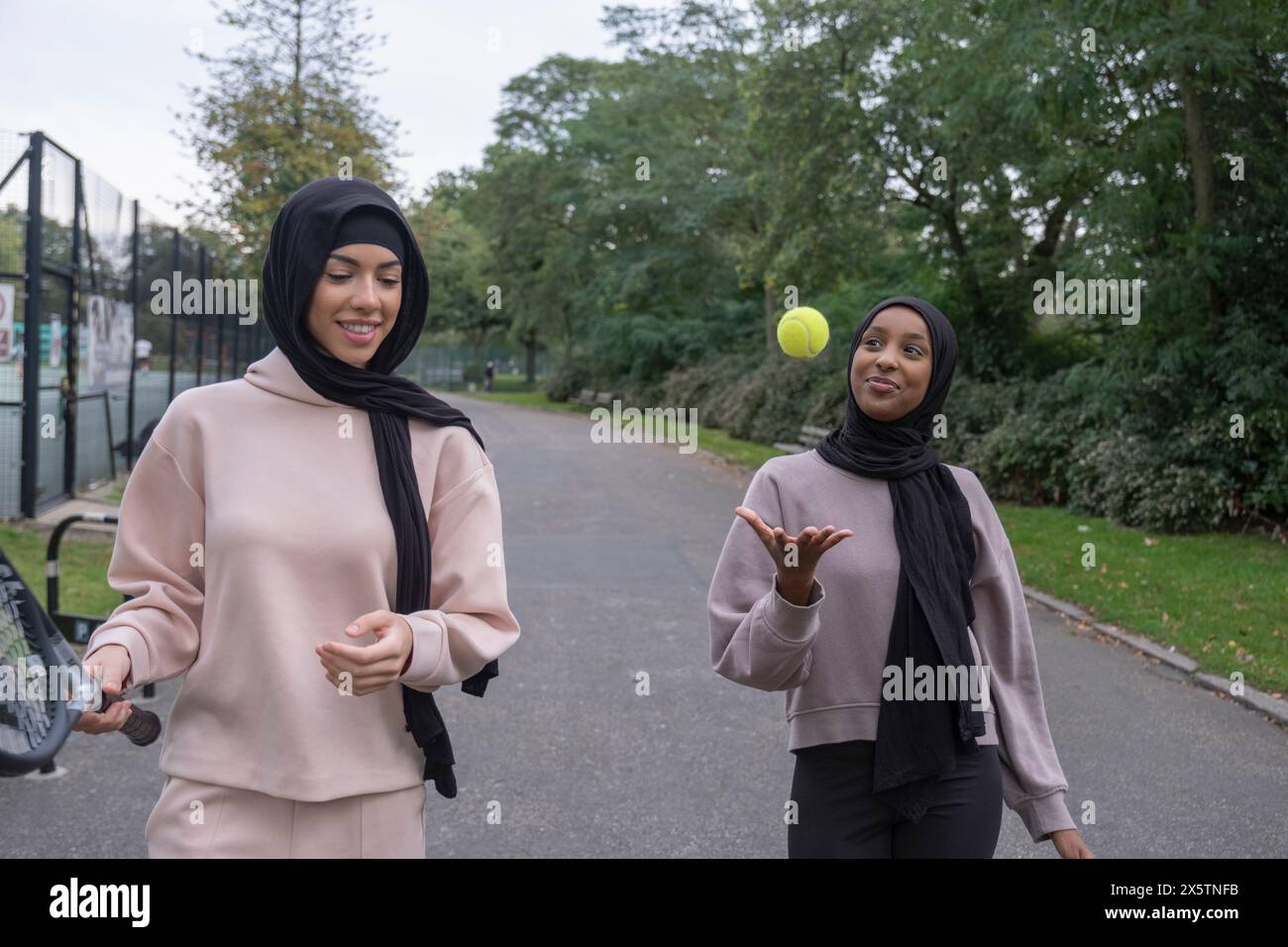Two women in hijabs walking in park with tennis racket and ball Stock Photo - Alamy
