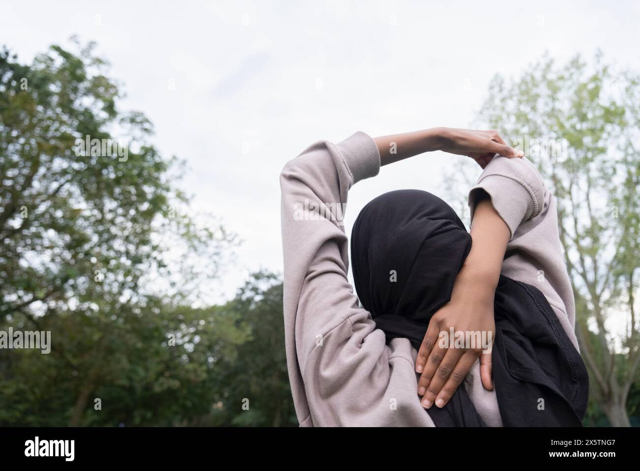 Rear view of woman in hijab stretching in park Stock Photo - Alamy