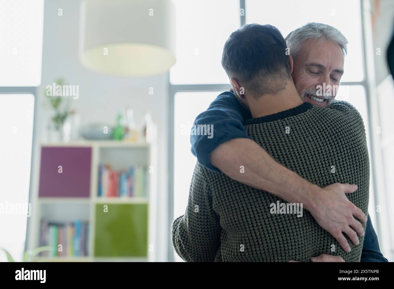Male couple hugging at home Stock Photo - Alamy