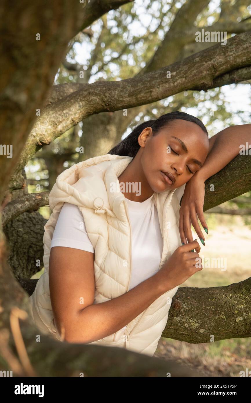 Portrait of young woman leaning on tree branch with eyes closed Stock ...