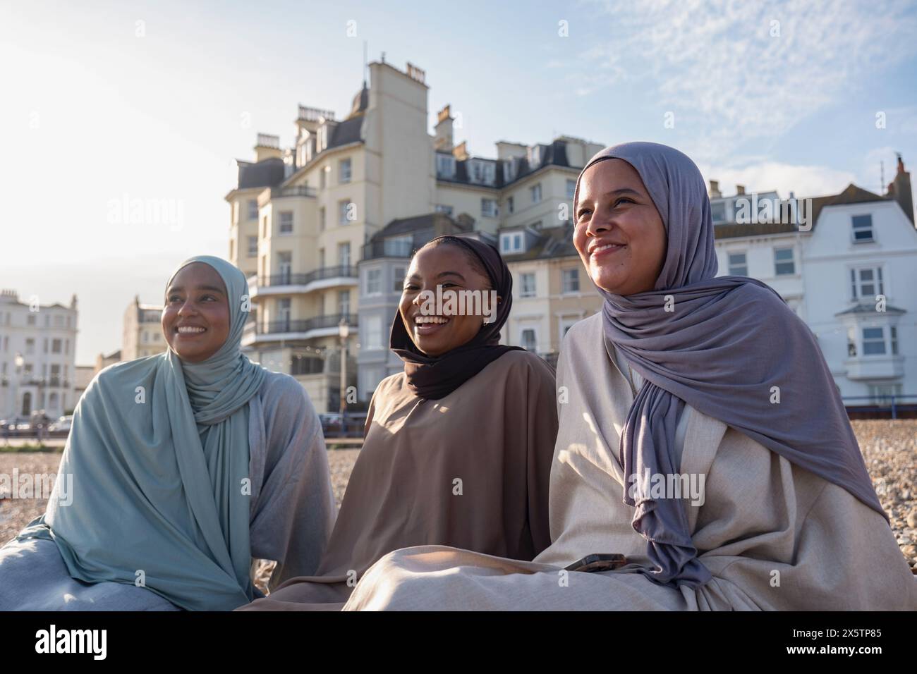Three Muslim friends sitting on beach Stock Photo - Alamy