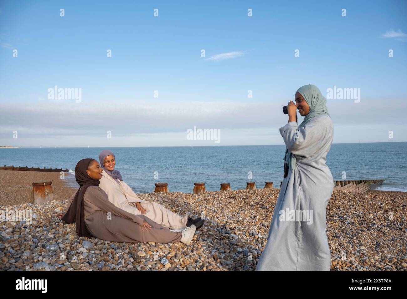 Woman photographing Muslim friends on beach Stock Photo - Alamy
