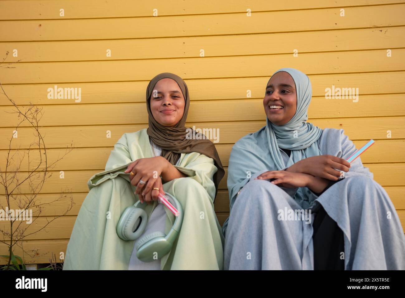 Portrait of Muslim friends sitting by yellow wall Stock Photo - Alamy