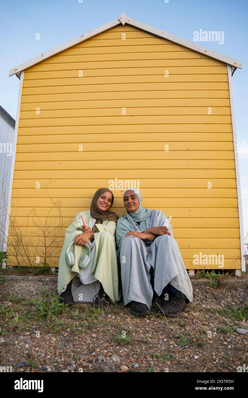 Two Muslim friends sitting by beach hut Stock Photo - Alamy