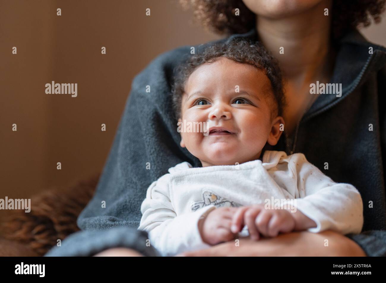 Smiling baby girl sitting on mothers lap Stock Photo - Alamy