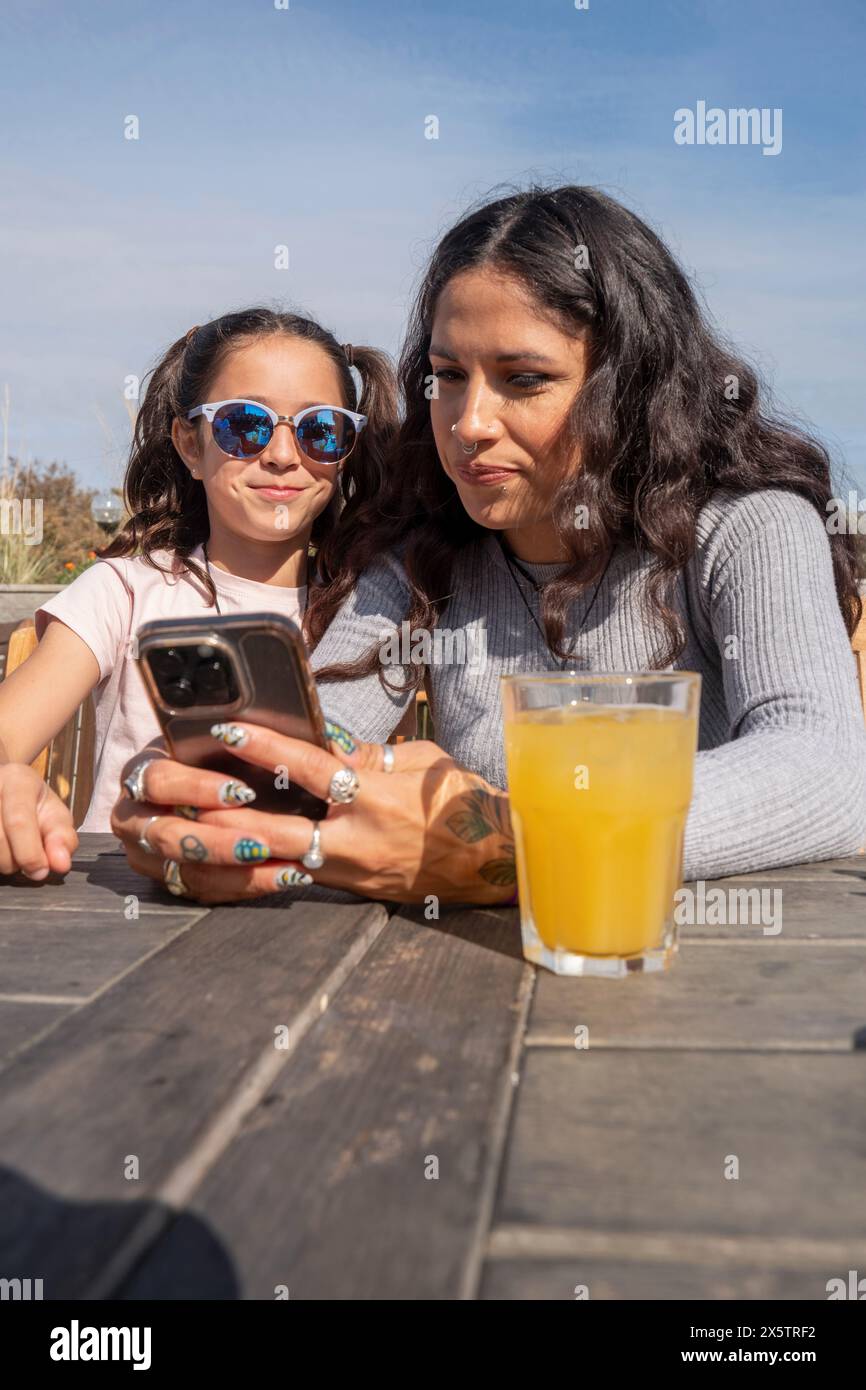 Mother and daughter using smart phone in outdoor restaurant Stock Photo ...