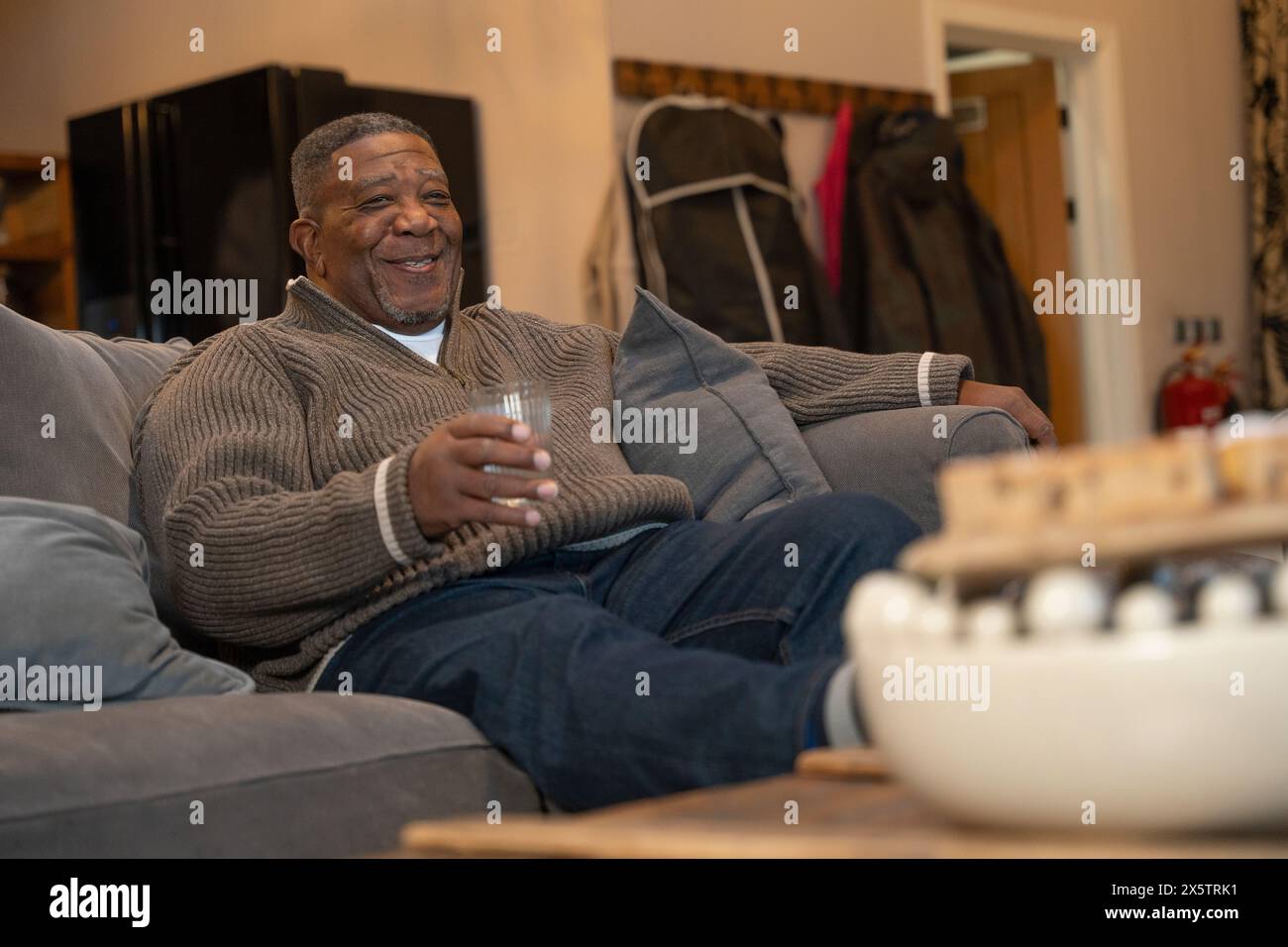Cheerful man sitting on sofa hi-res stock photography and images - Alamy