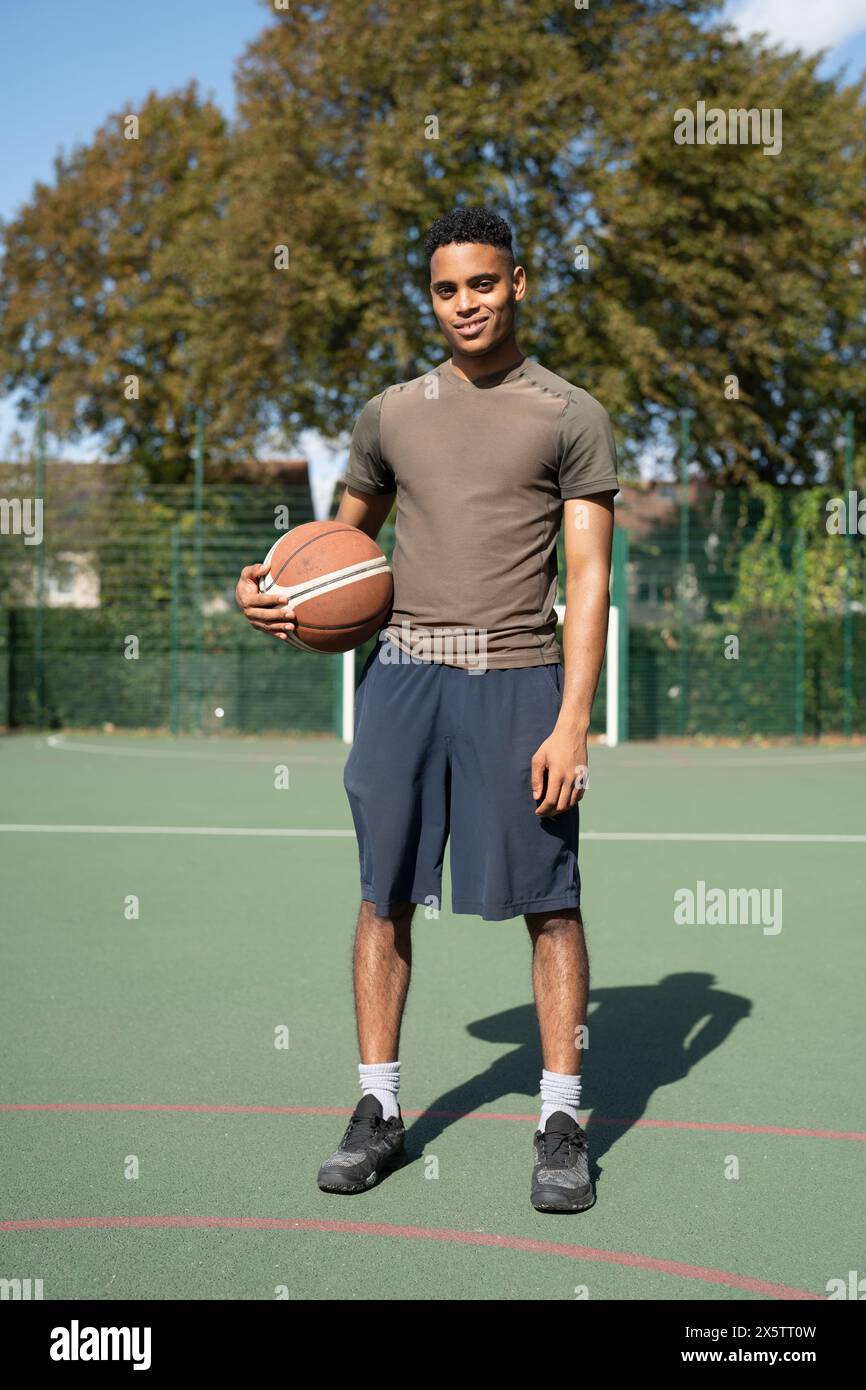 Portrait of smiling man with basketball ball in basketball court Stock ...