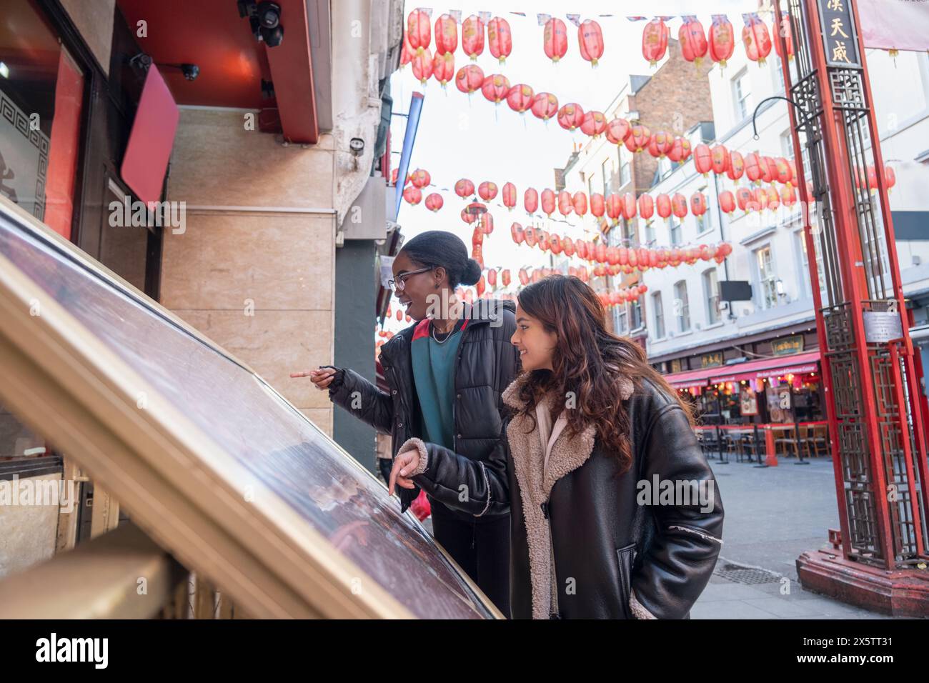 Two women checking menu at street restaurant in Chinatown Stock Photo ...