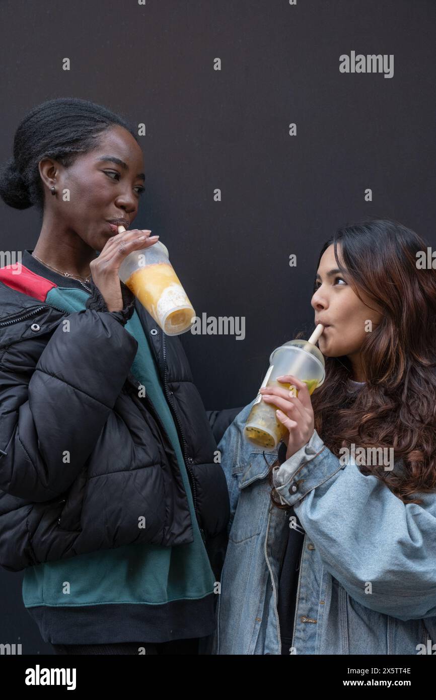 Portrait of two cheerful women drinking bubble tea Stock Photo - Alamy
