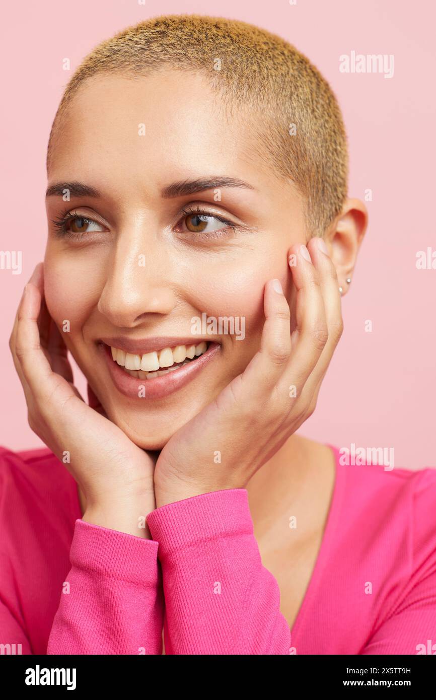 Smiling blond woman holding hands on cheeks Stock Photo - Alamy