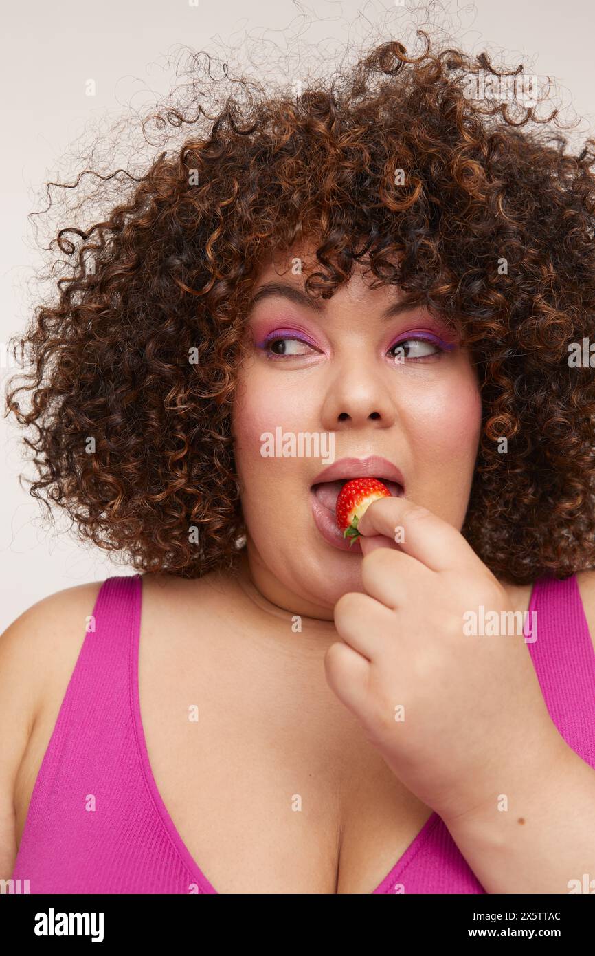 Brunette woman eating strawberry Stock Photo - Alamy
