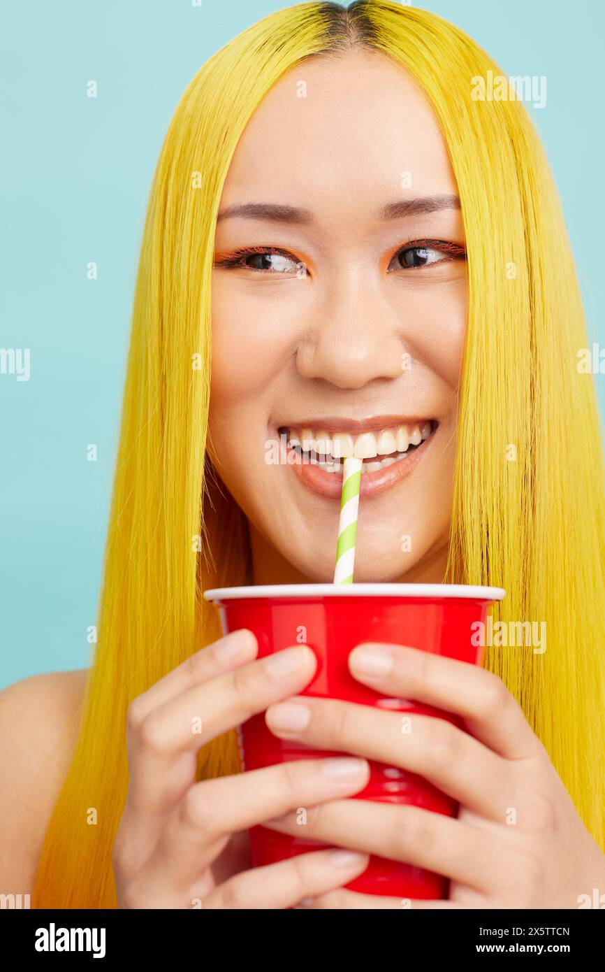 Smiling young woman with long yellow hair, drinking through straw Stock ...