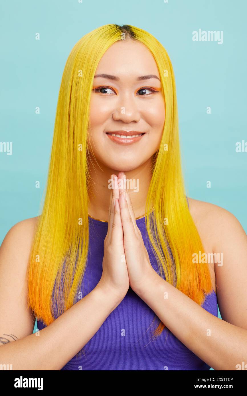 Smiling woman with long yellow hair, holding clasped hands Stock Photo ...
