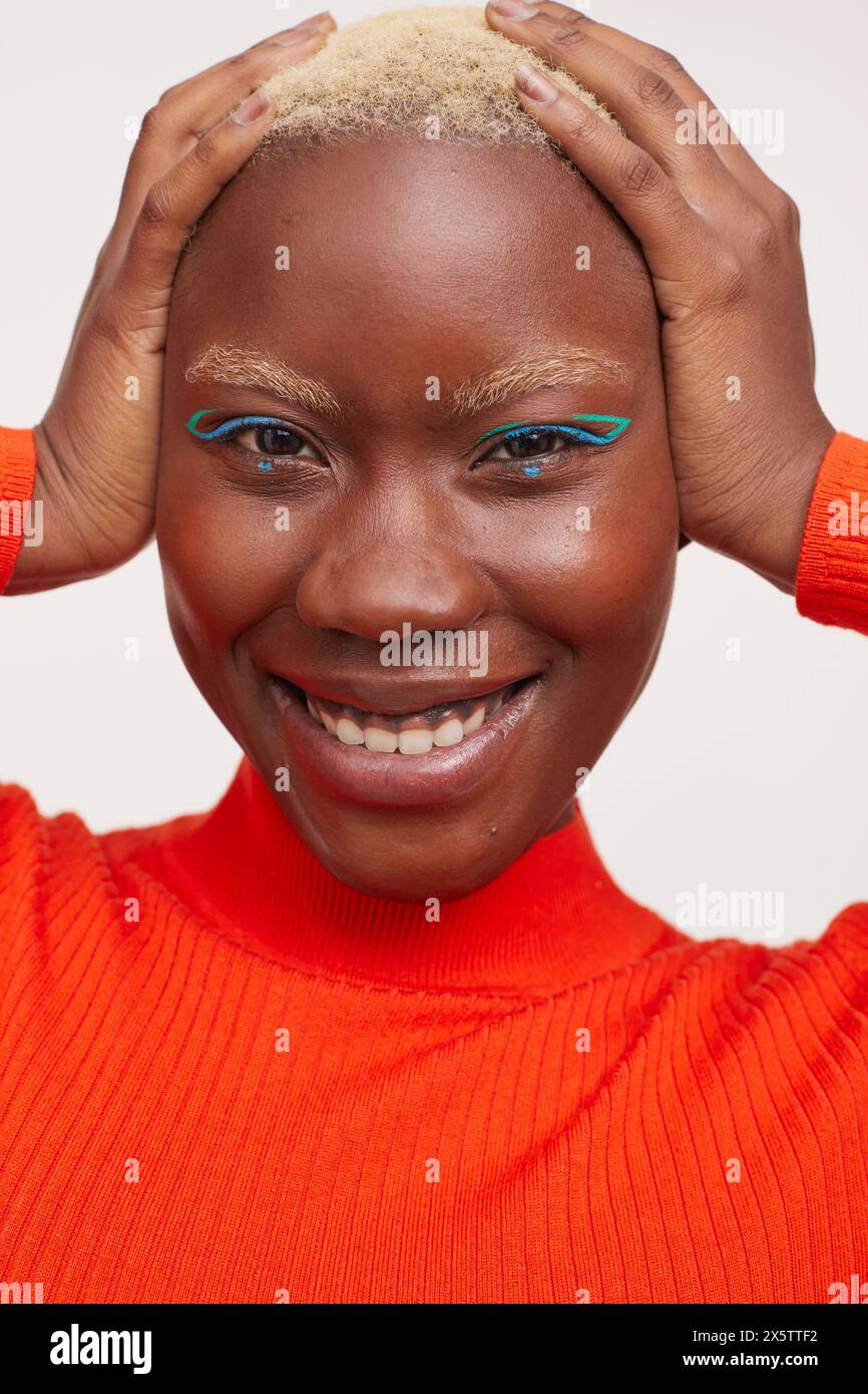 Woman with short white hair and blue make up, holding hand on head ...