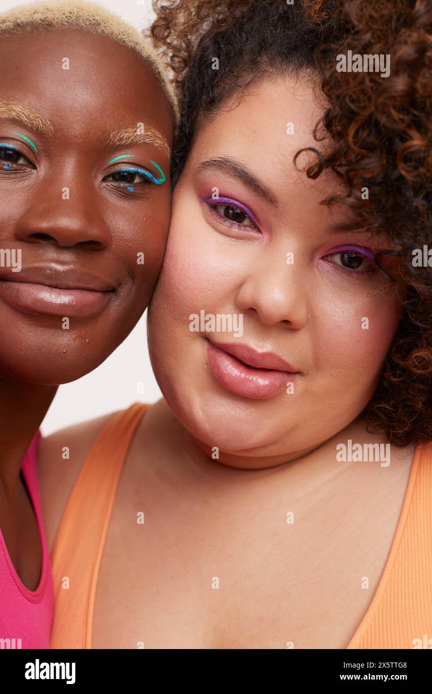 Portrait of two young women wearing make up, cheek to cheek Stock Photo ...