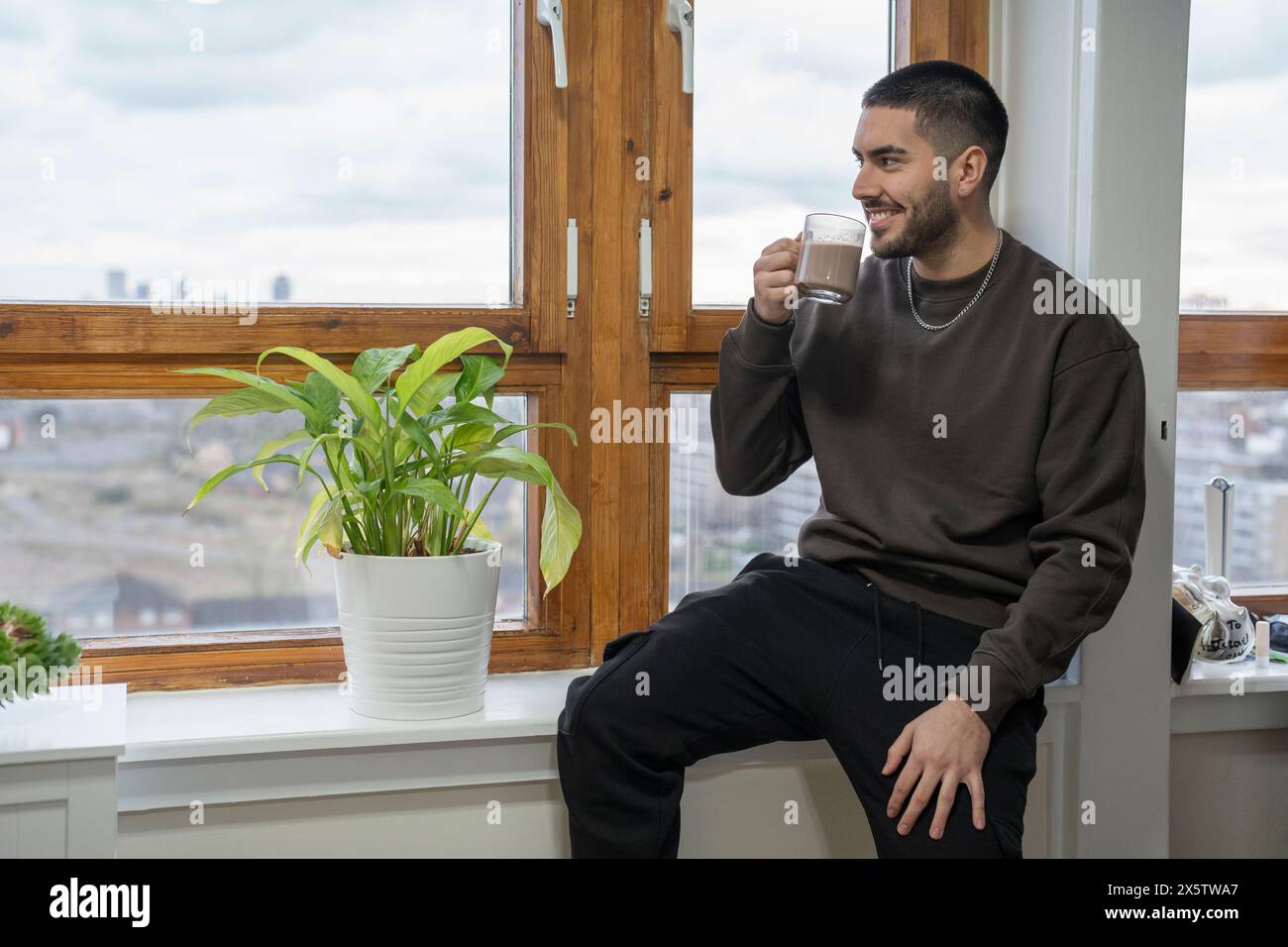 Smiling young man drinking milk tea at home Stock Photo - Alamy