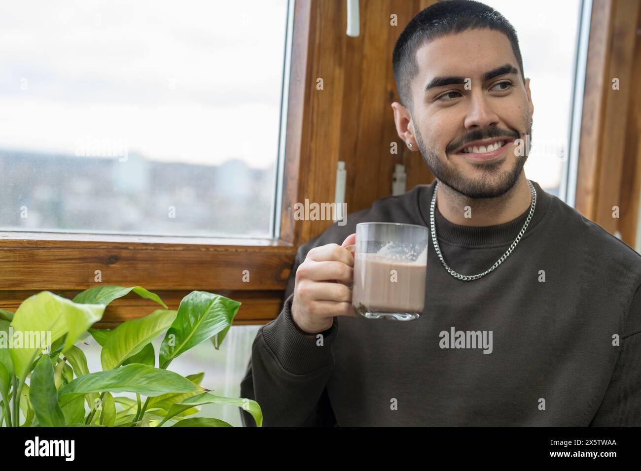 Smiling young man drinking milk tea at home Stock Photo - Alamy