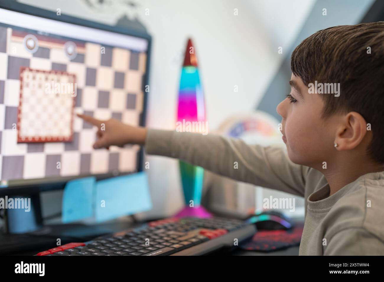 Boy (6-7) playing chess on computer Stock Photo - Alamy
