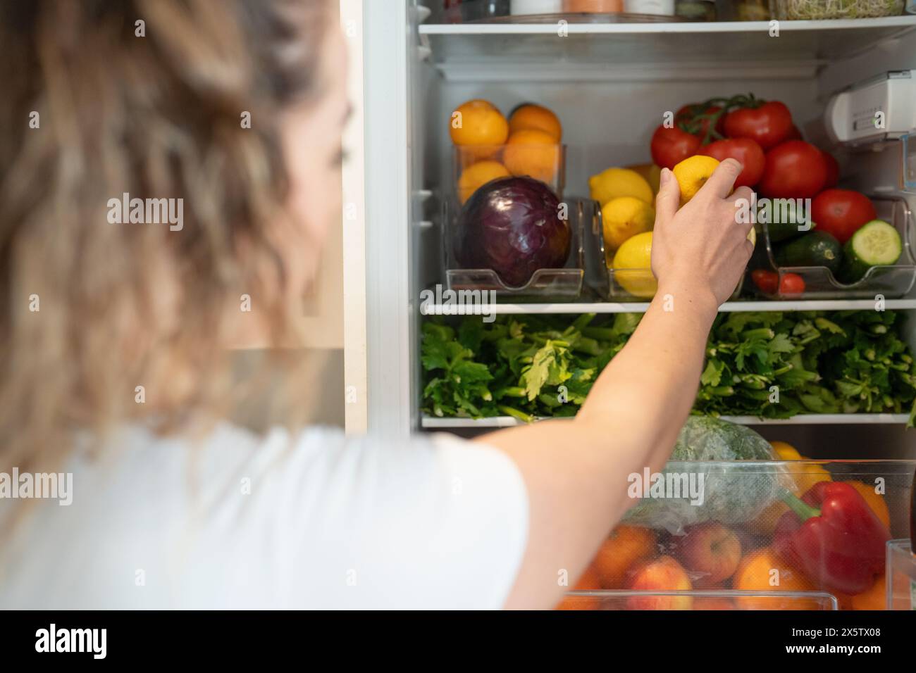 Woman opening fridge and picking fruit Stock Photo - Alamy