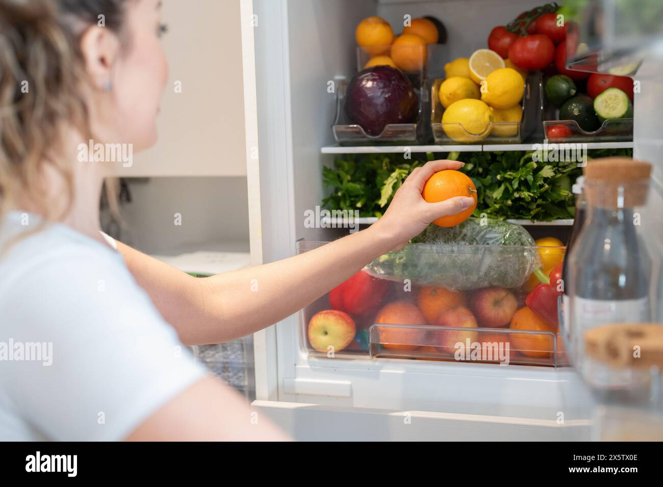 Woman opening fridge and picking fruit Stock Photo - Alamy