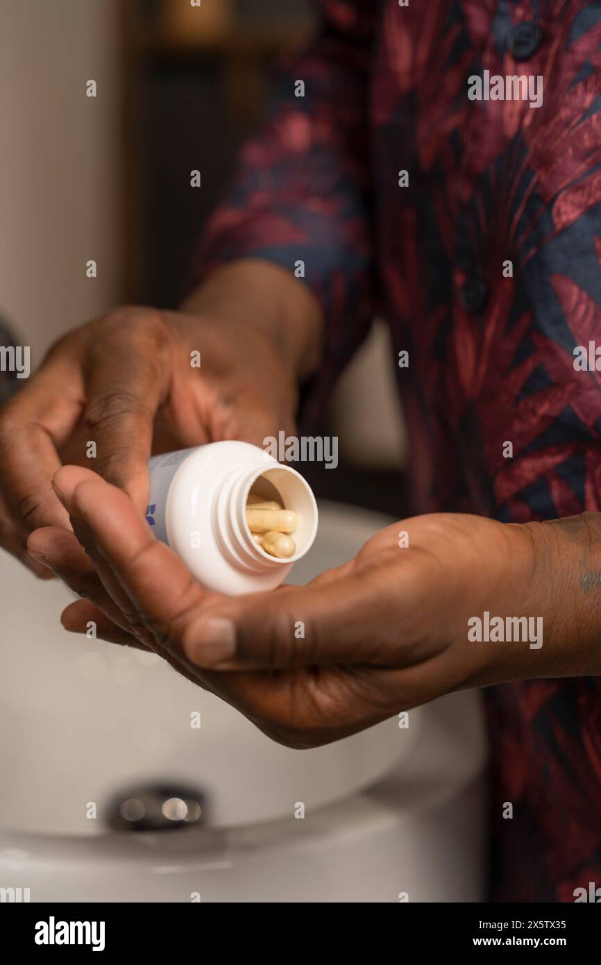 Man taking pills while standing next to bathroom sink Stock Photo - Alamy