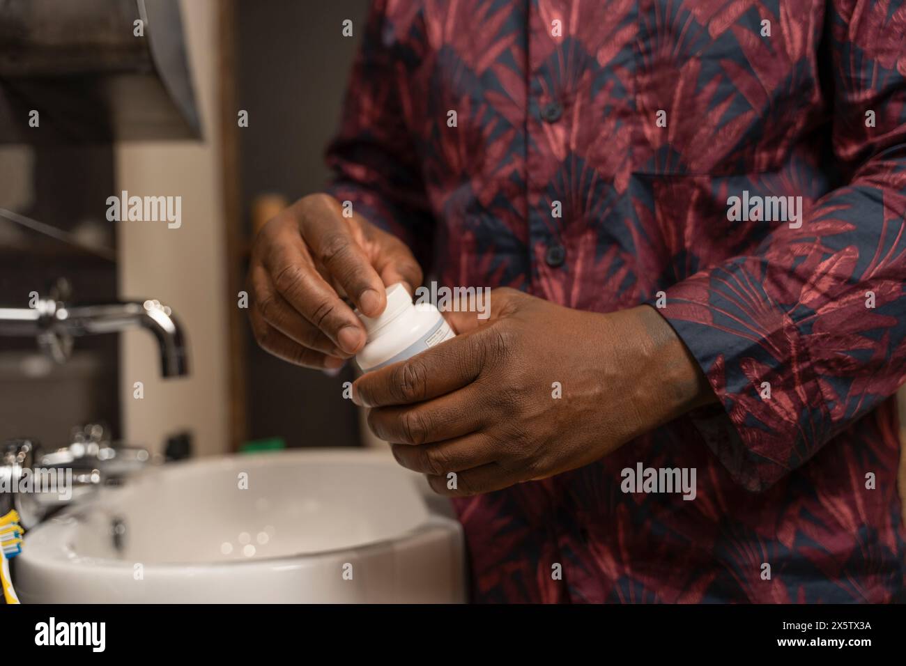Man opening pill bottle while standing next to bathroom sink Stock ...
